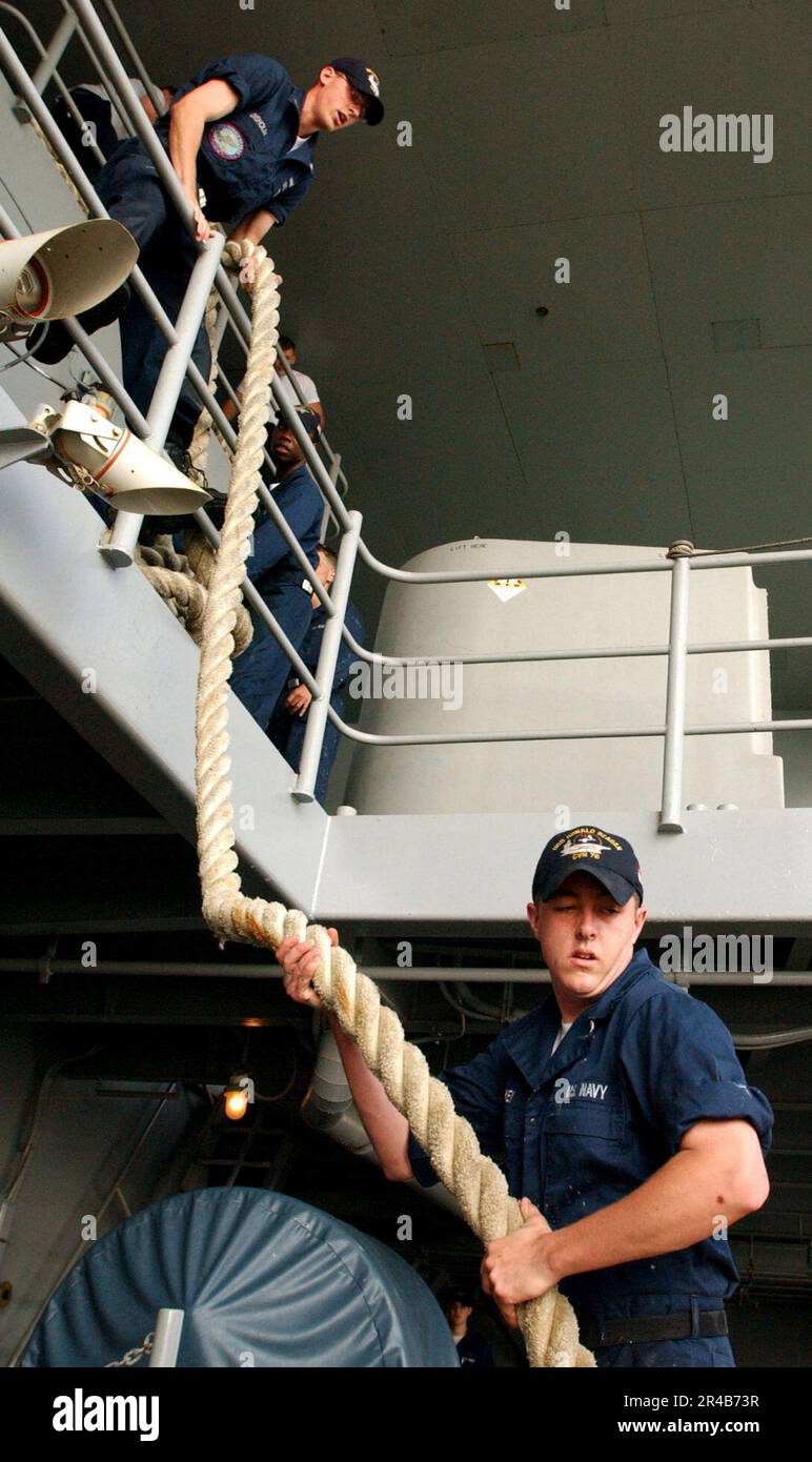 US Navy Seaman bottom, guides a mooring line to Boatswain's Mate 3rd ...
