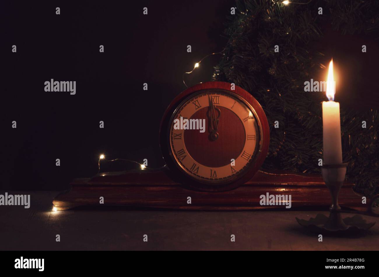 Vintage old wooden clock, yellow candle and Christmas tree branch on ...