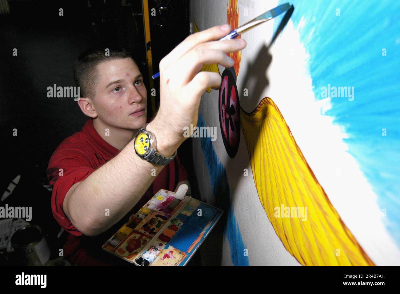 US Navy Aviation Ordnanceman Airman paints a mural on a bulkhead in the ...
