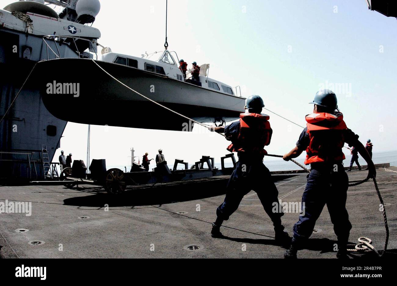 US Navy Sailors direct the Captain's Gig as it's raised back aboard the ...