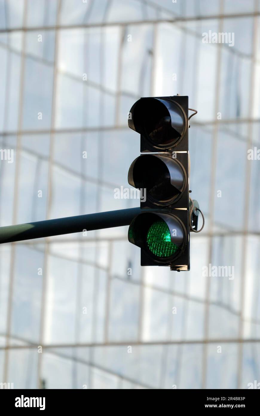 Grenn traffic light in front of the glass facade of an office building ...