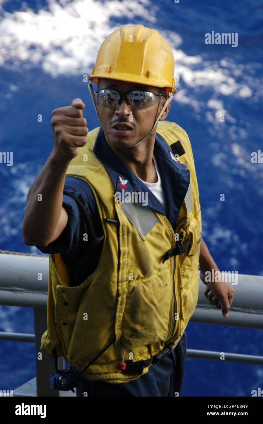 US Navy Boatswain's Mate 1st Class signals the winch operator to stop ...