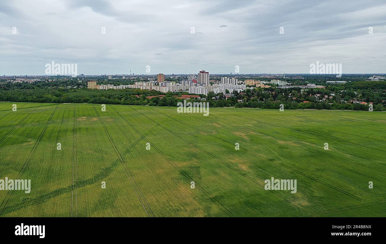 An aerial view of a green field with city buildings in the background ...