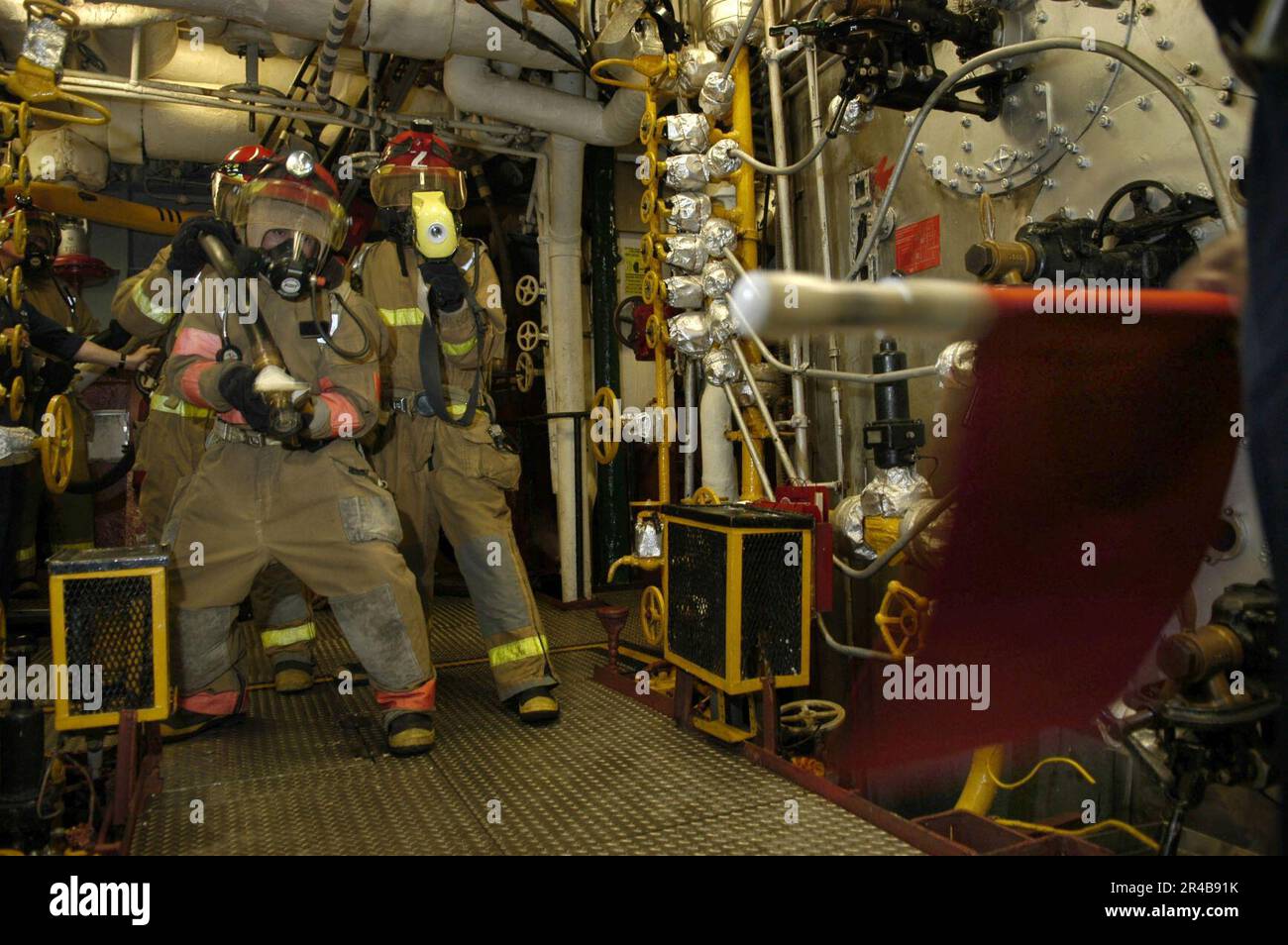 US Navy Hose team members fight a simulated fire-filled space during a ...