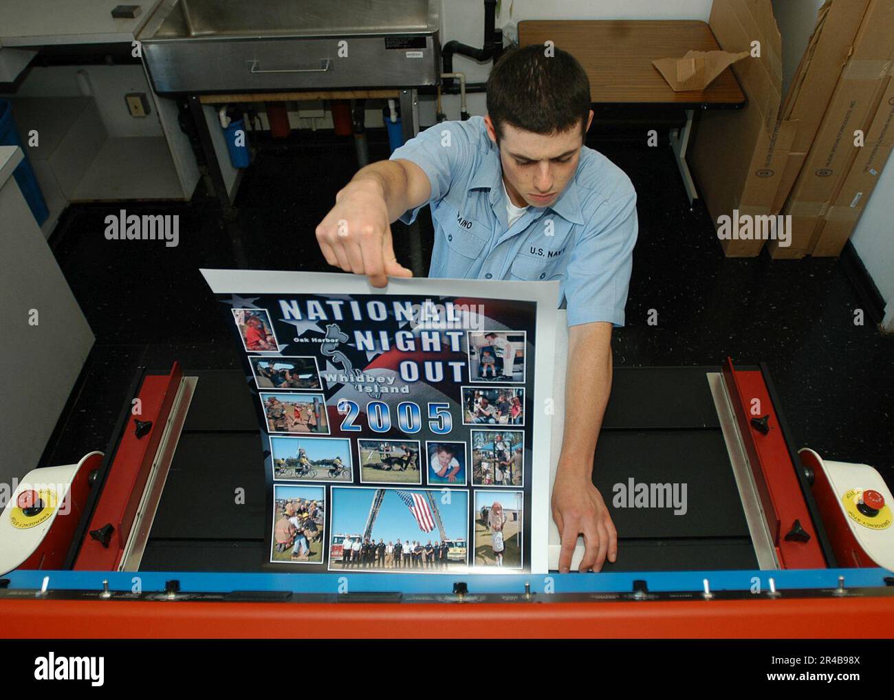 US Navy Photographers Mate Airman laminates a poster for the National ...