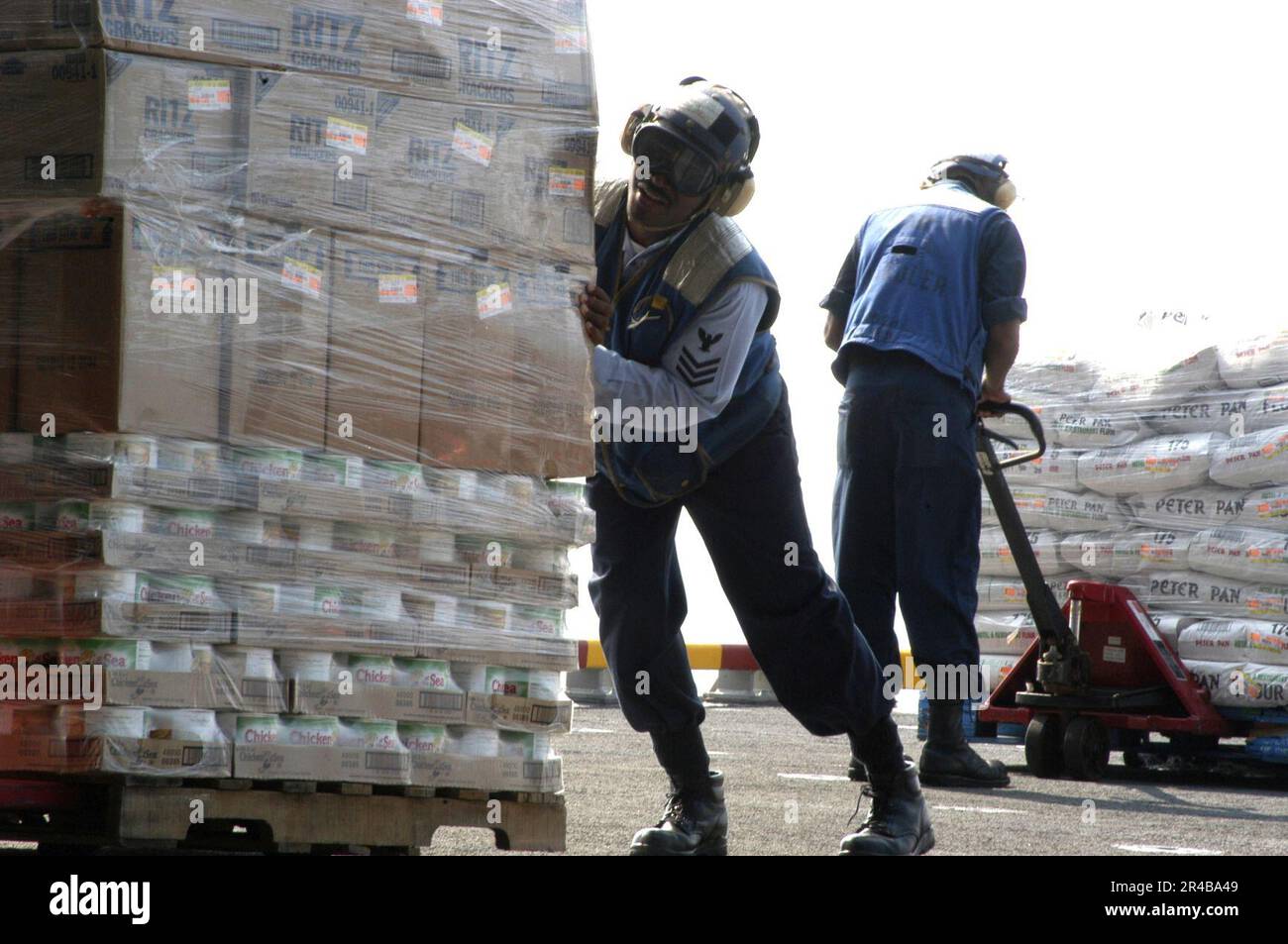 US Navy Culinary Specialist 1st Class helps move pallets of food on the ...