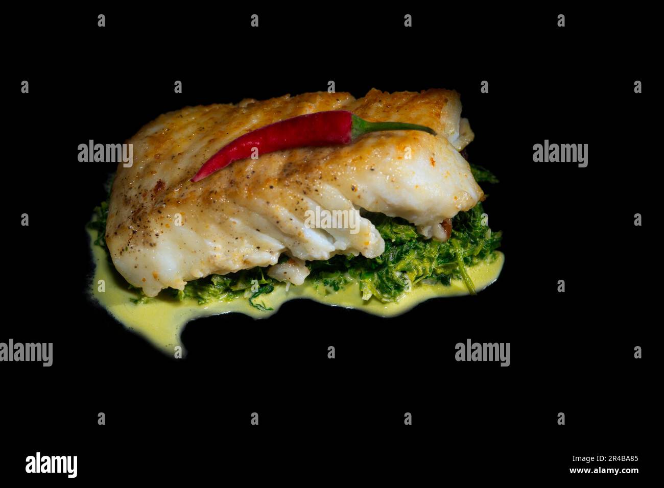 Cod fillet fried in nut butter on leaf spinach with a red chilli, food ...