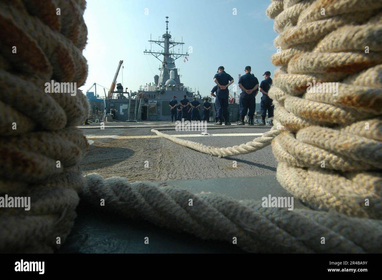 US Navy Sailors stand at parade rest as they prepare to cast off lines ...