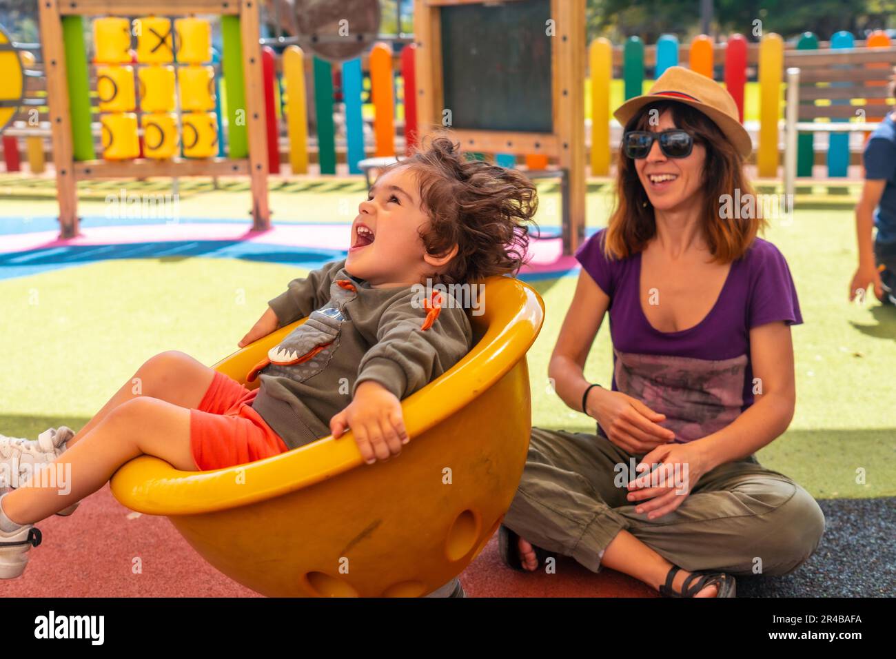 Mother having fun with her son in a playground laughing Stock Photo - Alamy