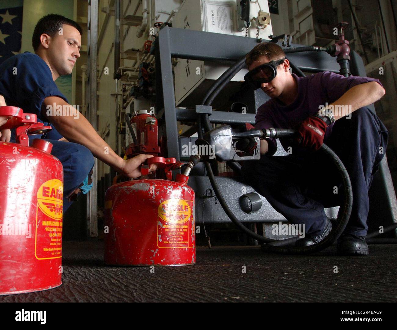 US Navy Airman assigned to Air Department's V-4 (Fuels) Division, fills gasoline cans with JP-5 ...