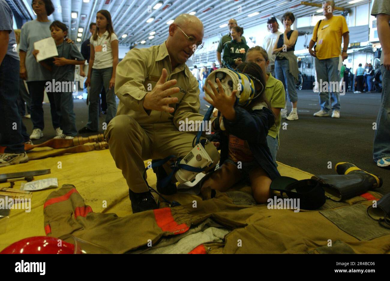 US Navy Senior Chief Storekeeper explains to a young child how a Naval ...