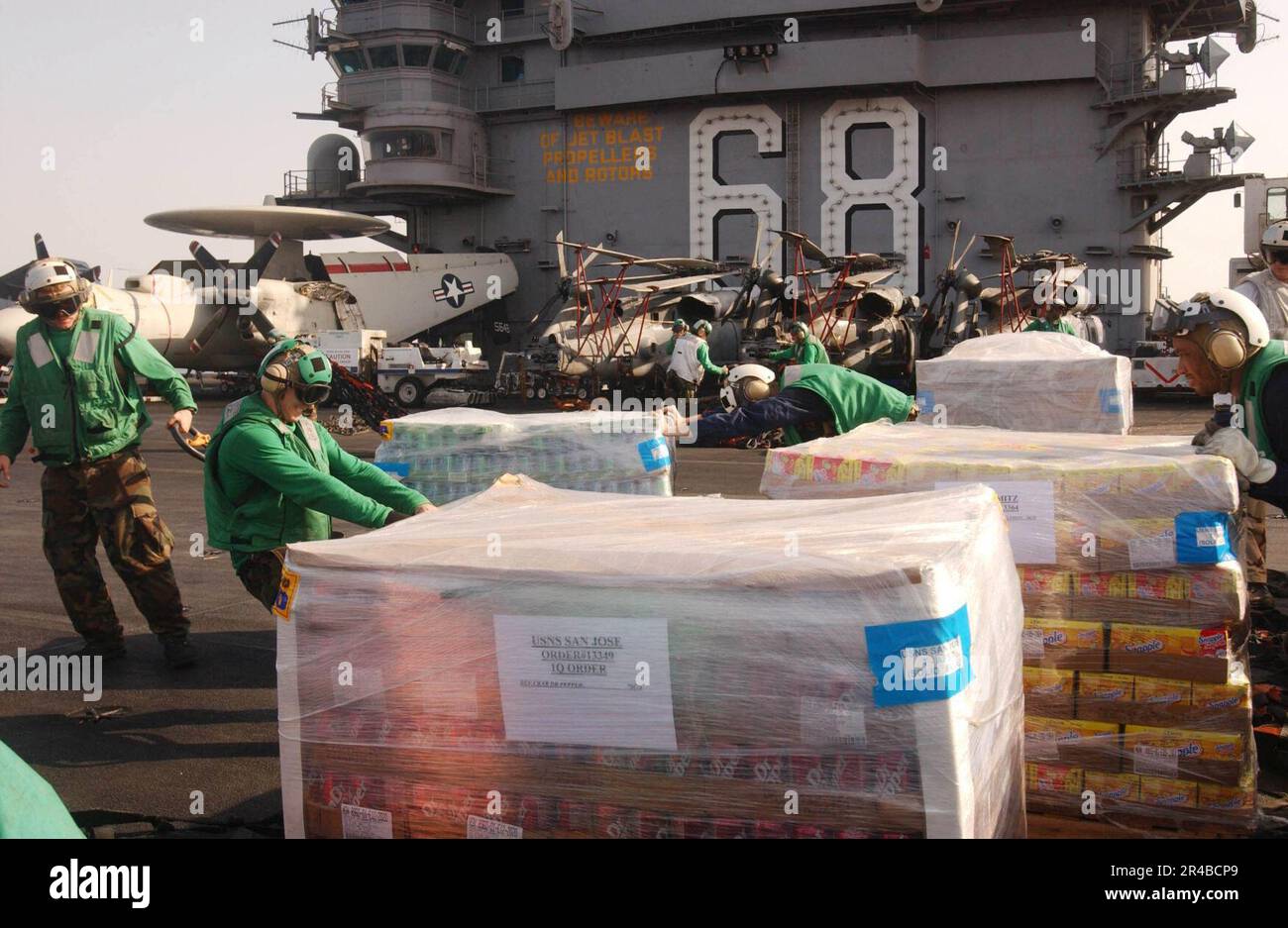 US Navy Crew members move pallets of supplies aboard the nuclear ...