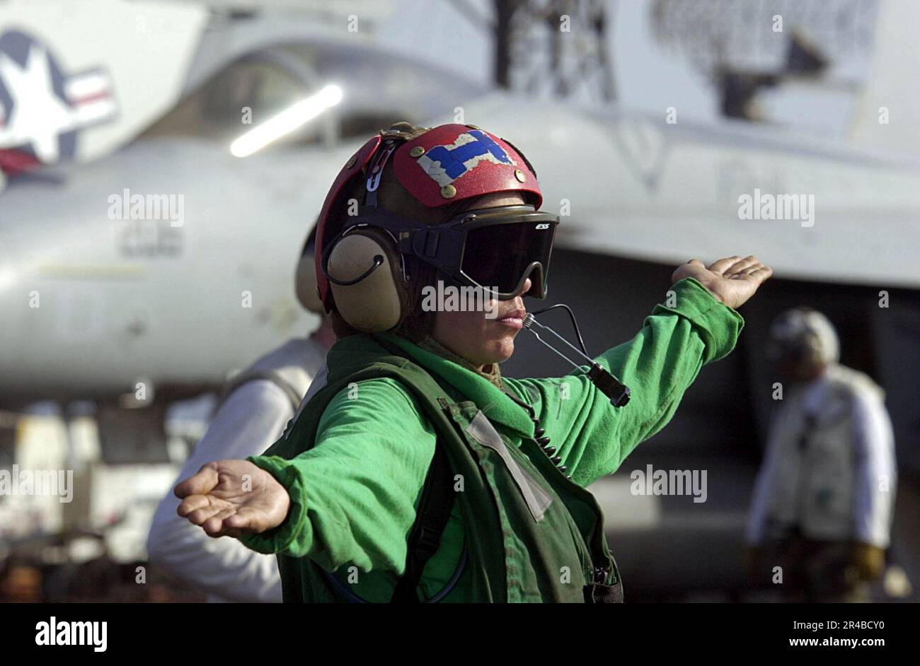 US Navy Storekeeper 3rd Class signals to an MH-60S Seahawk helicopter ...