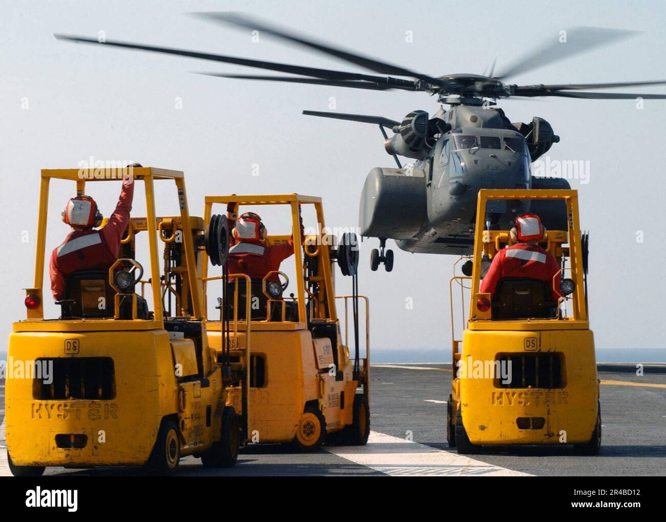 US Navy Sailors manning forklifts prepare to load supplies into an MH ...