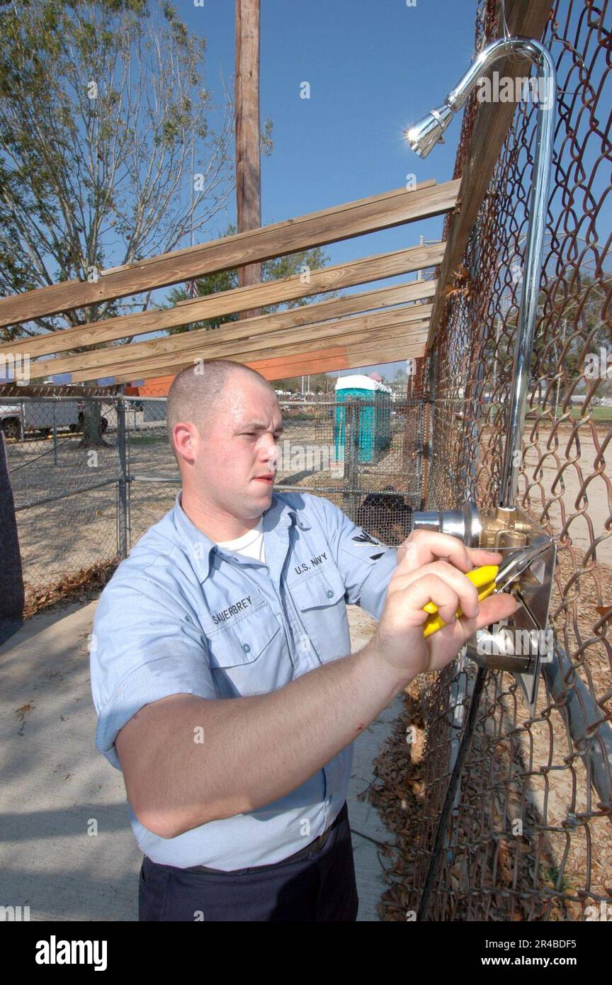 US Navy Hull Technician 3rd Class attaches a shower assembly to a ...