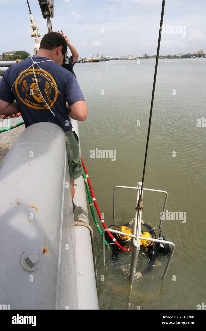 US Navy Divers are lifted out of the water after patching and ...