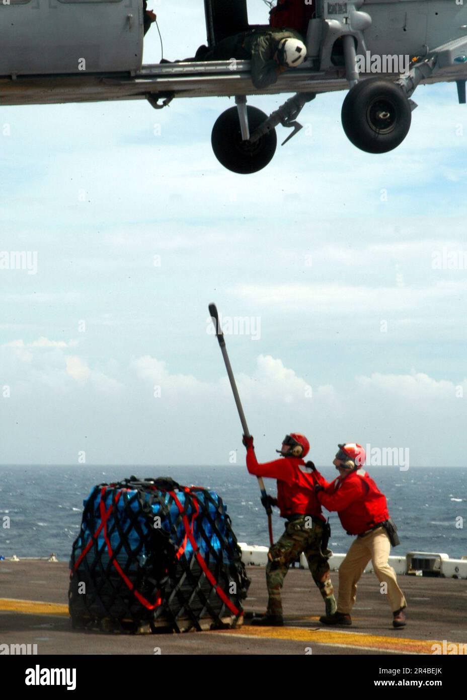 US Navy Air Department personnel prepare to hook a cargo pendant to an ...