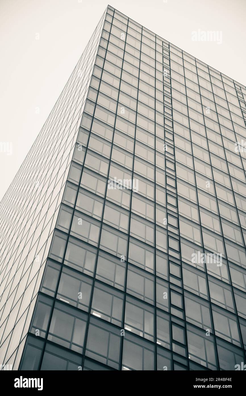 A modern glass skyscraper stands tall in an urban landscape, with an ...