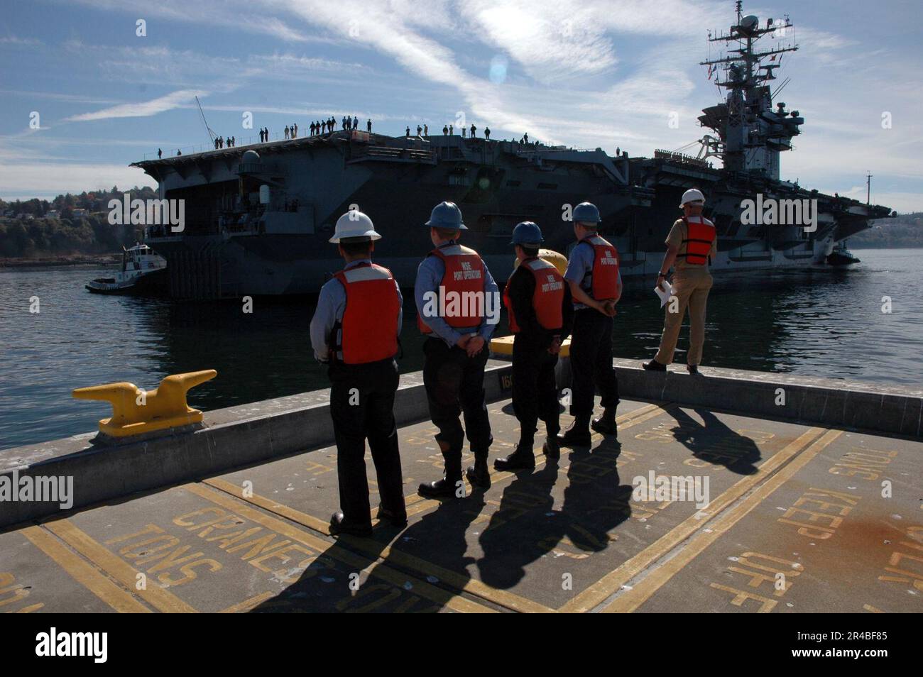US Navy Line handlers standby as the Nimitz-class aircraft carrier USS ...