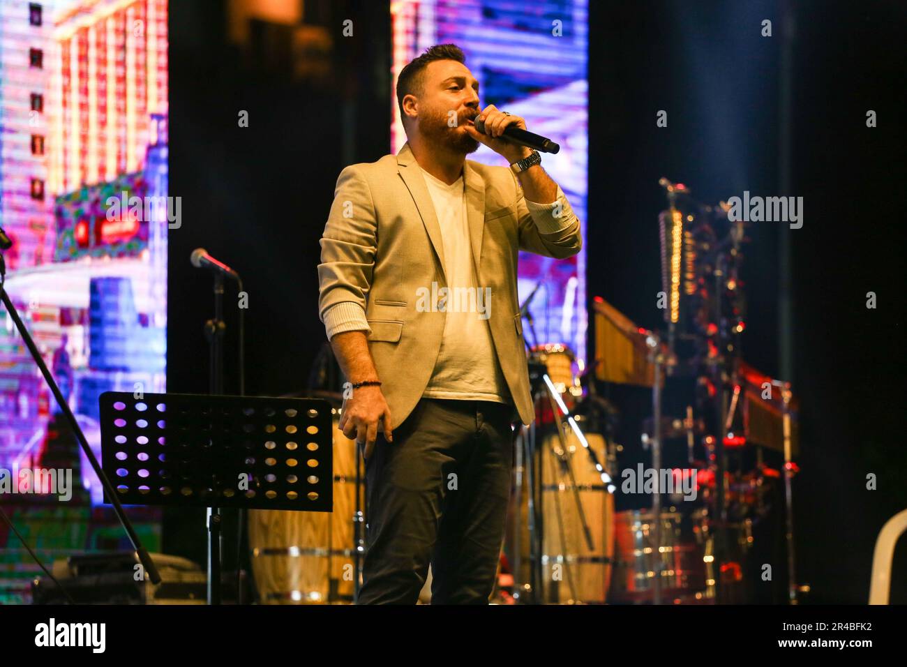 A Caucasian male musician stands on a brightly lit stage in front of a ...