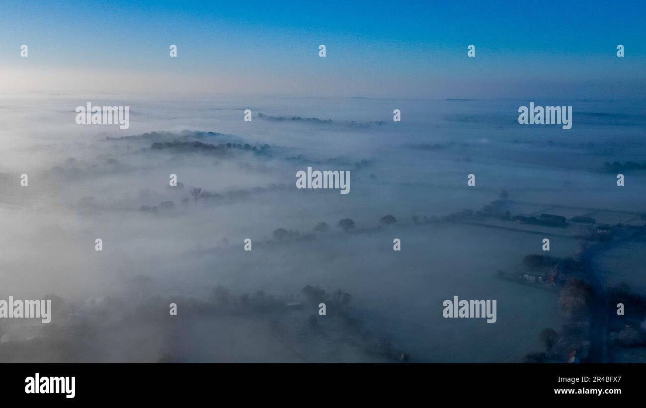 An aerial view of a small town shrouded in a misty fog, with white ...