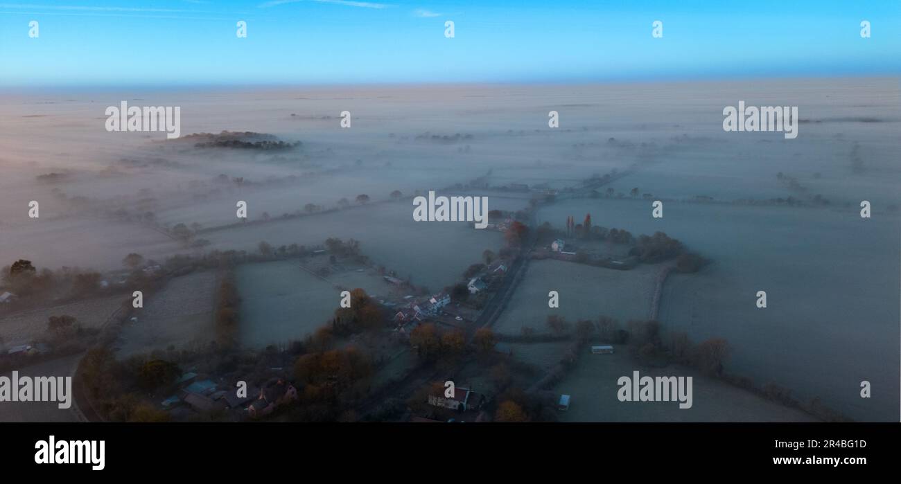 An aerial view of a small town shrouded in a misty fog, with white ...