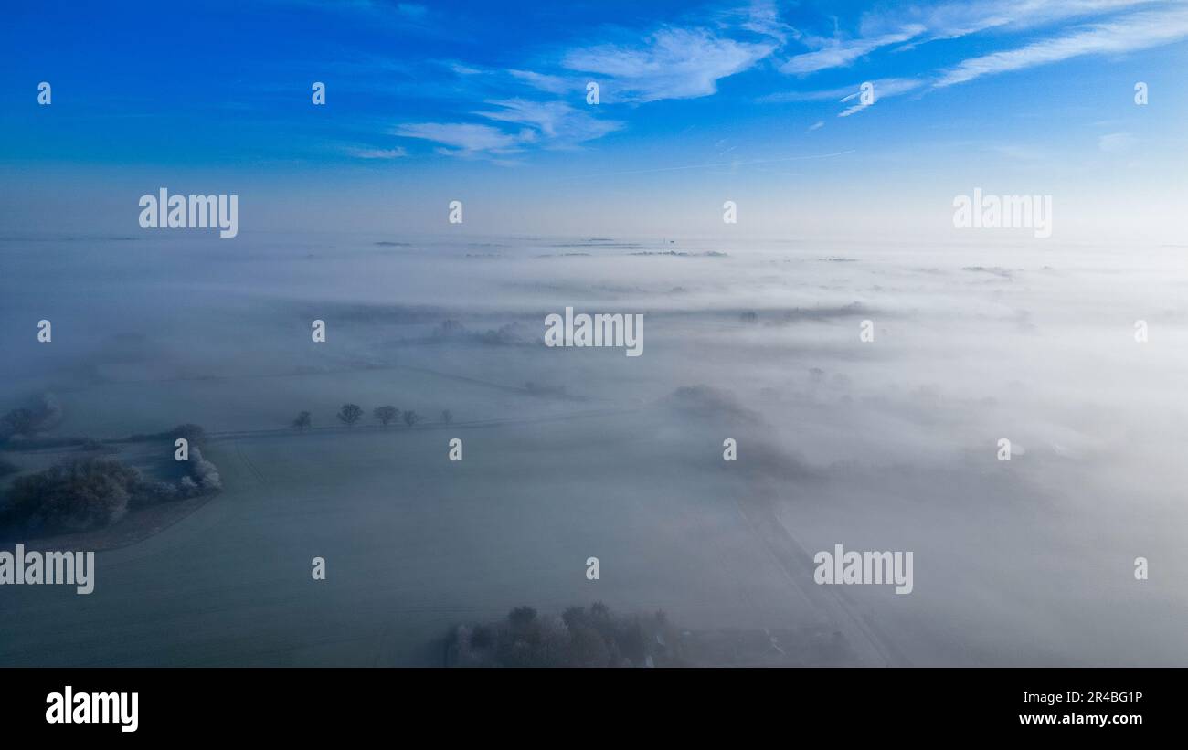 An aerial view of a small town shrouded in a misty fog, with white ...
