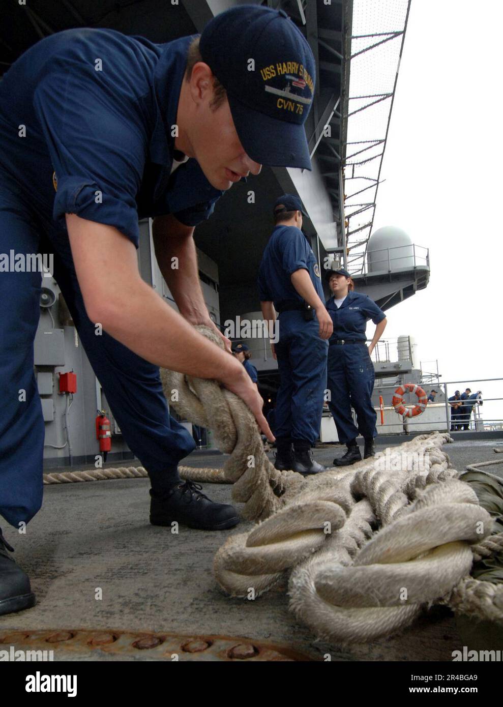 US Navy Seaman takes-in a mooring line on the fantail of the Nimitz ...