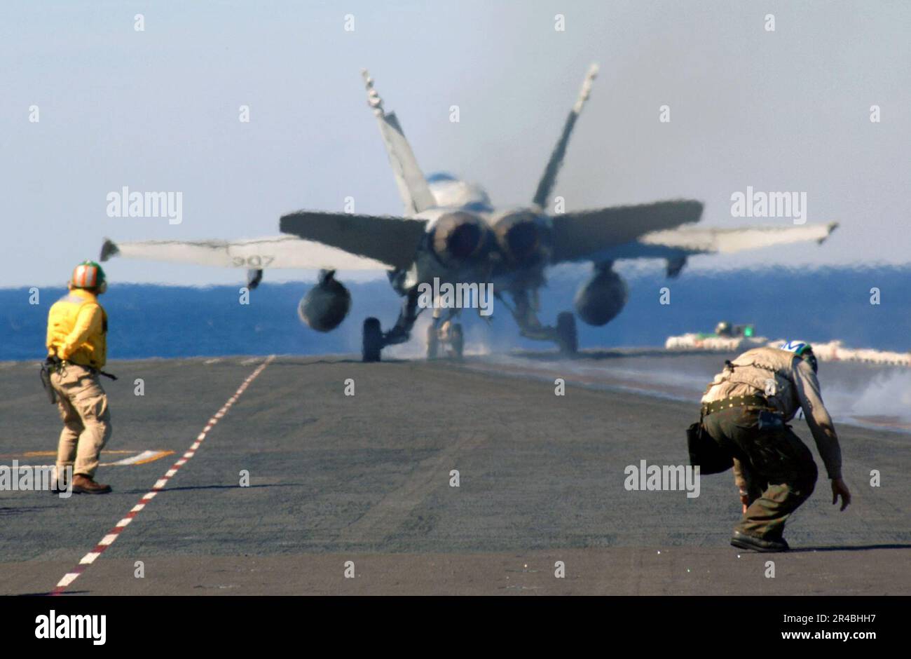 US Navy Flight deck personnel watch as an F-A-18C Hornet assigned to the Raging Bulls of Strike ...