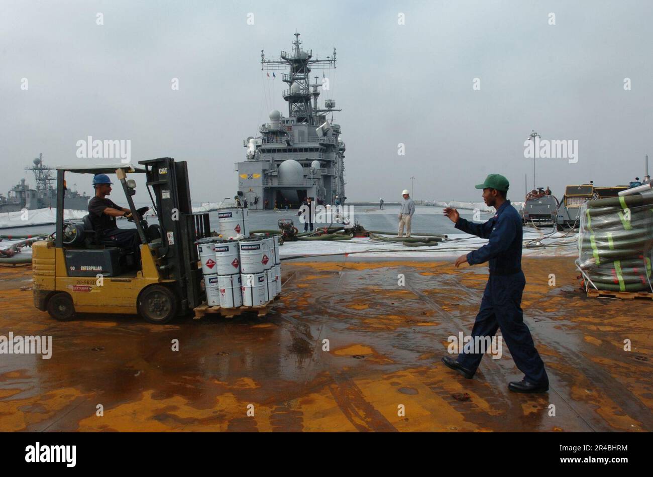 US Navy Boatswain's Mate 2nd Class right, directs a contractor on a ...