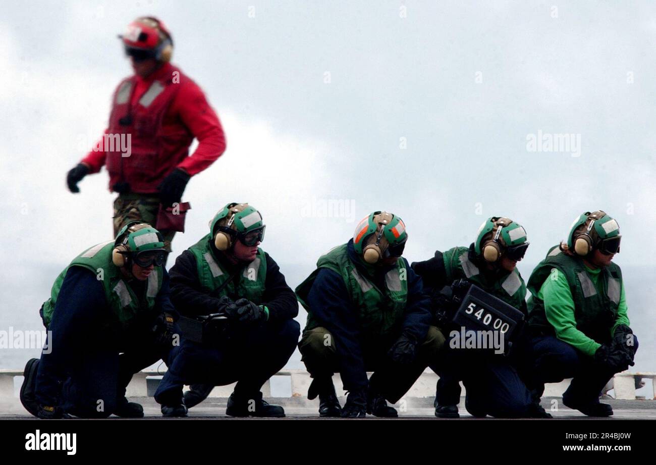 US Navy Flight deck personnel standby as an aircraft prepares to launch ...