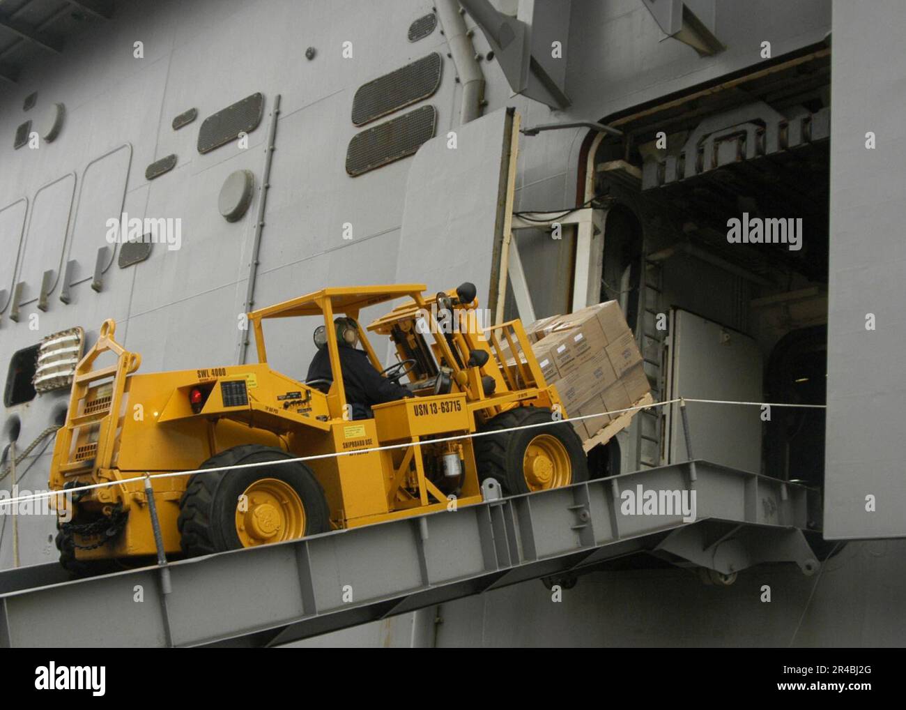 US Navy A crew member moves supplies up the ramp of the amphibious ...