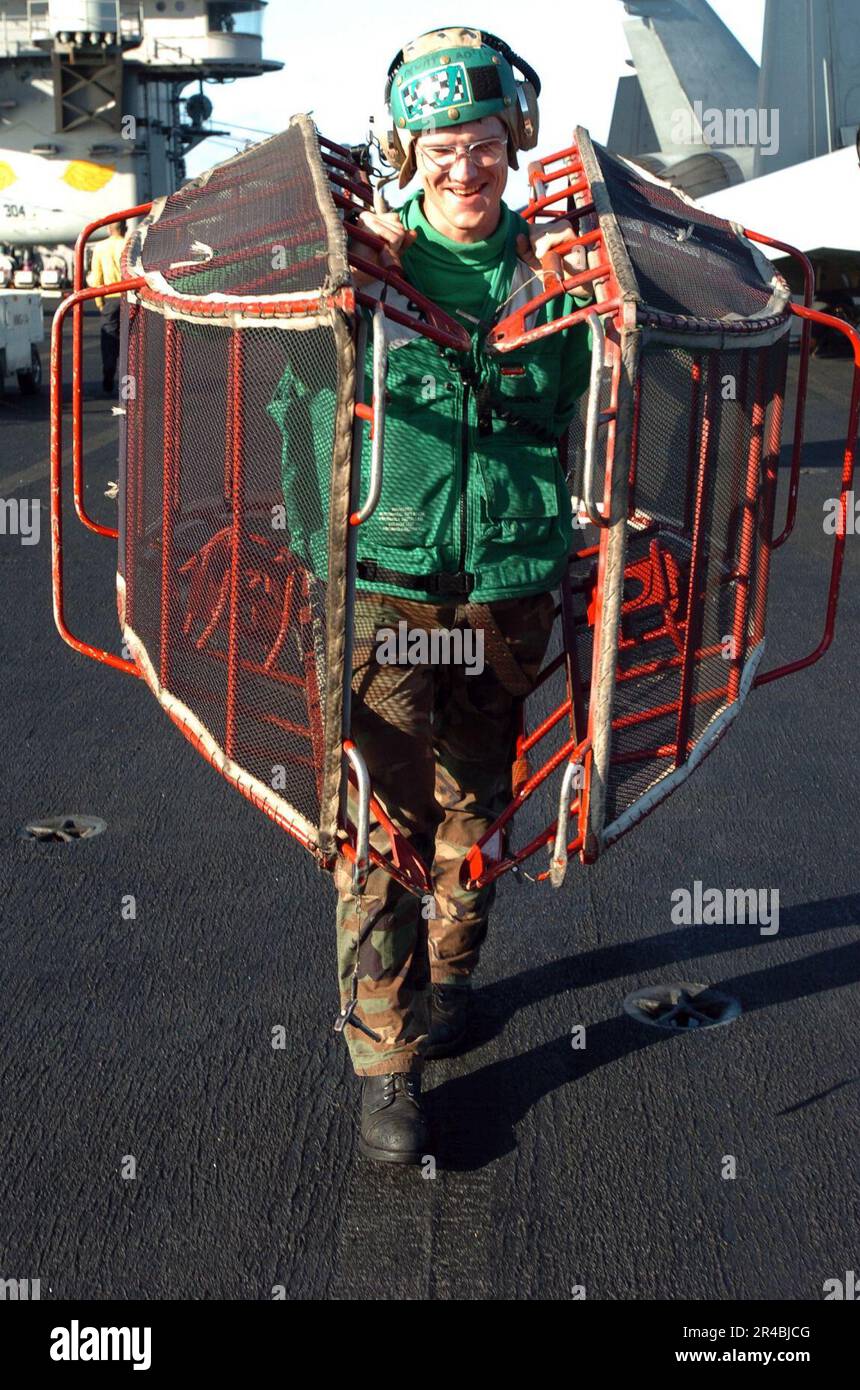 US Navy Airman carries jet intake protective covers across the flight ...