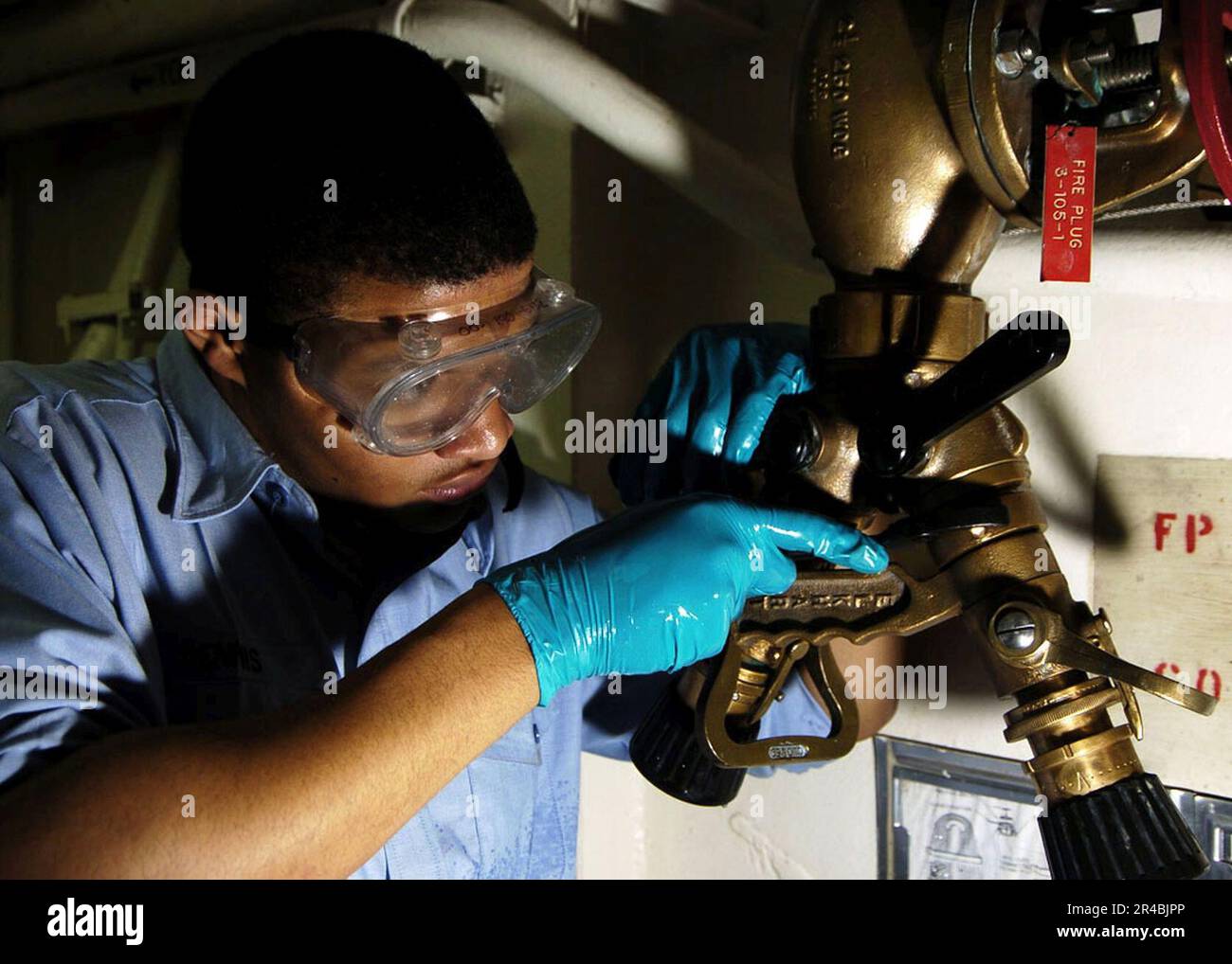 US Navy Photographer's Mate Airman performs a routine maintenance check ...