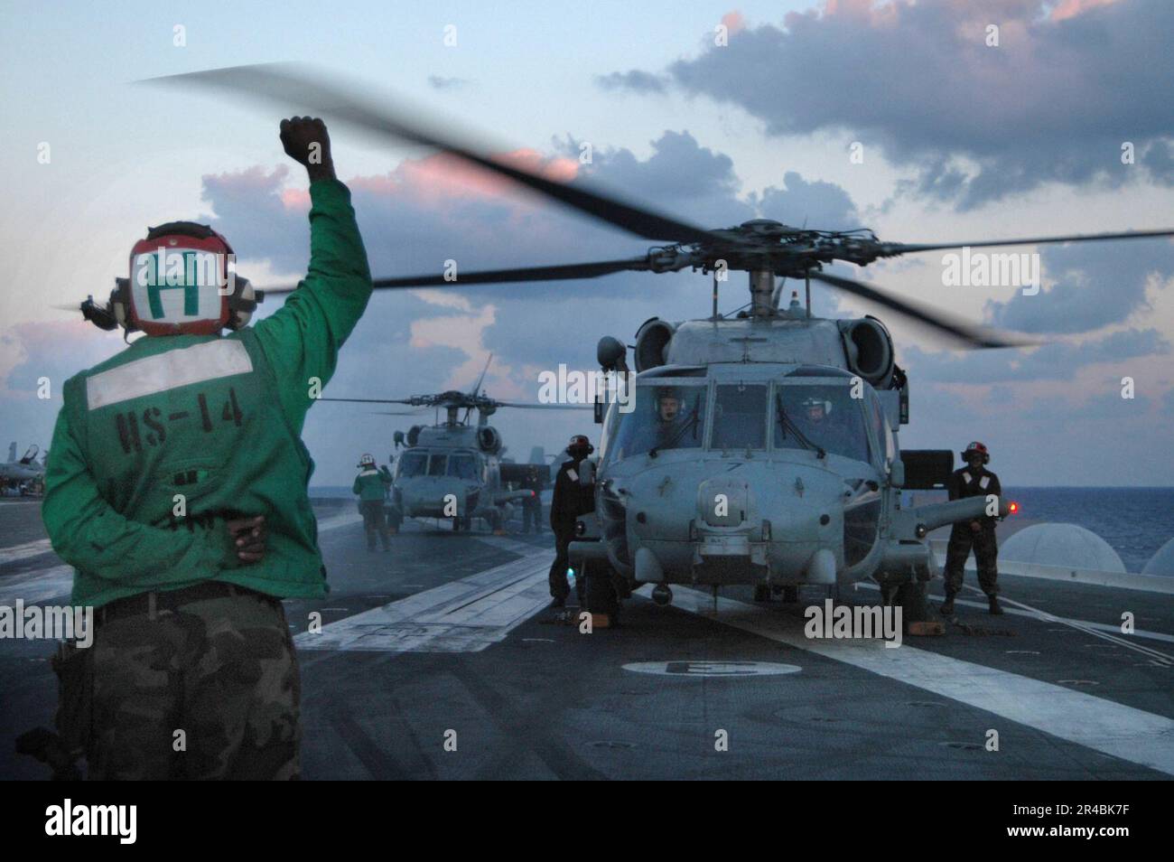 US Navy A Sailor assigned to Helicopter Anti-Submarine Squadron Fourteen (HS-14), signals to an ...