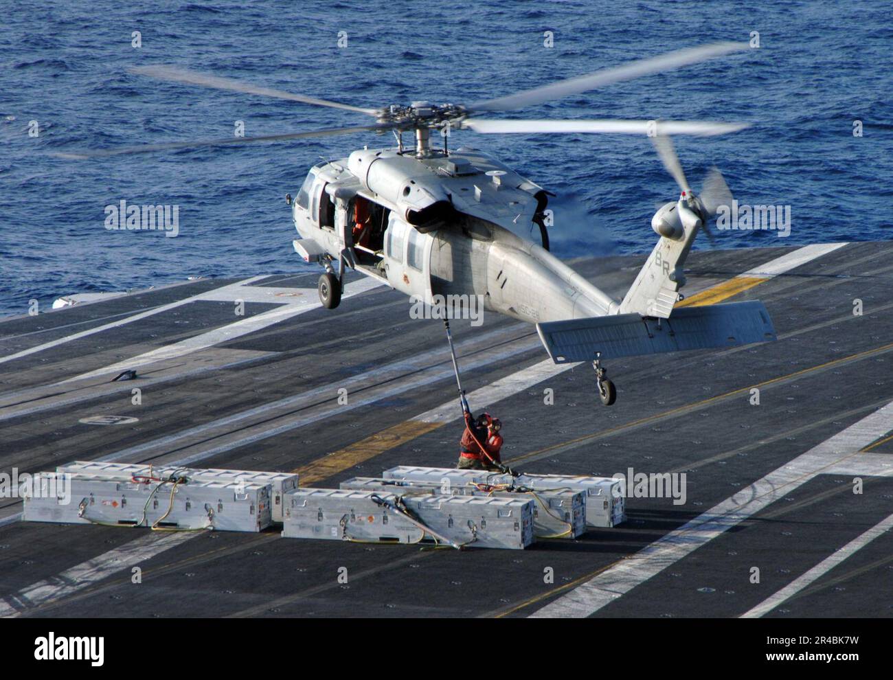 US Navy Aviation Ordnancemen attach ordnance to an MH-60S Seahawk ...