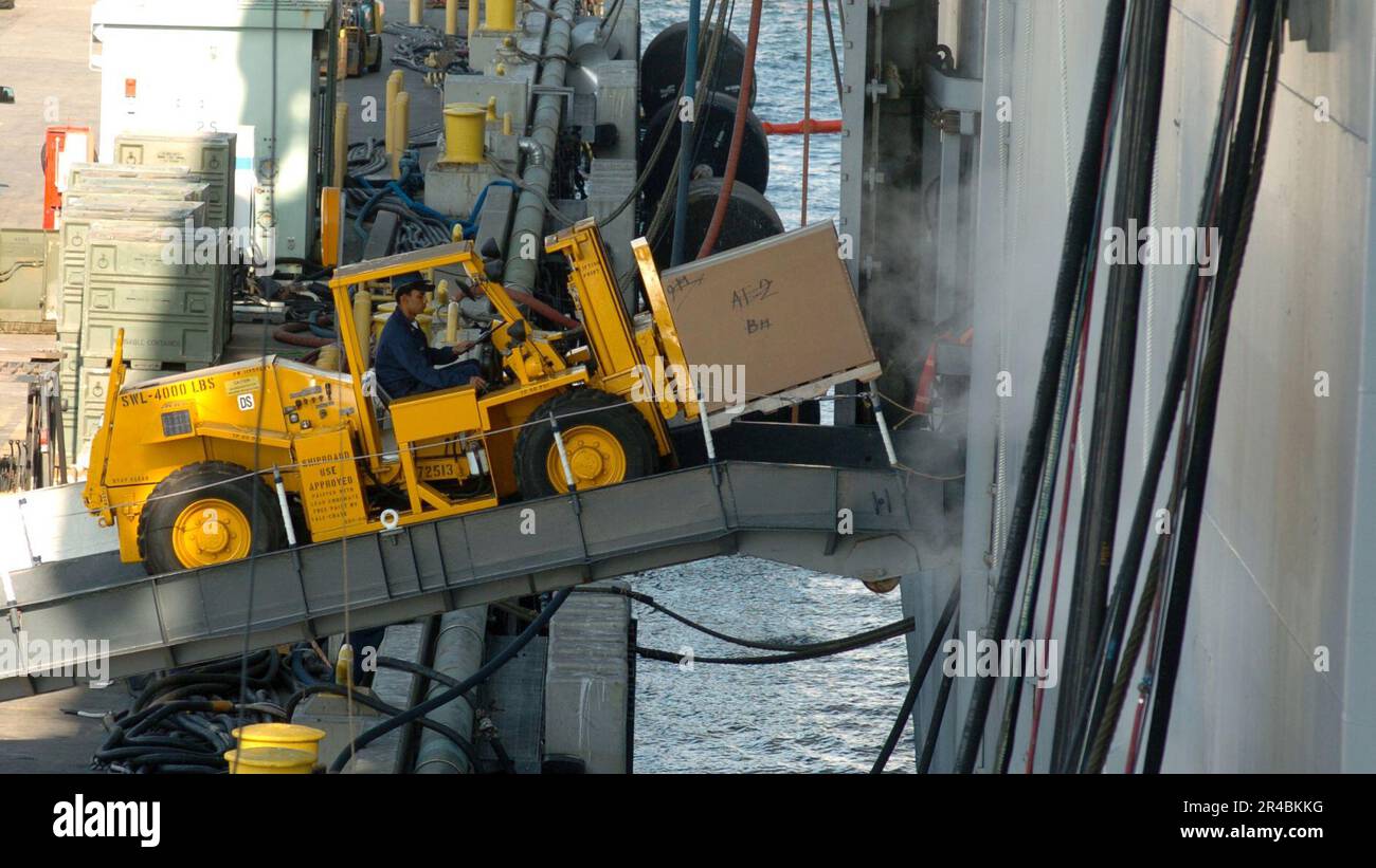 US Navy A Sailor drives his forklift loaded with cargo onto the ...