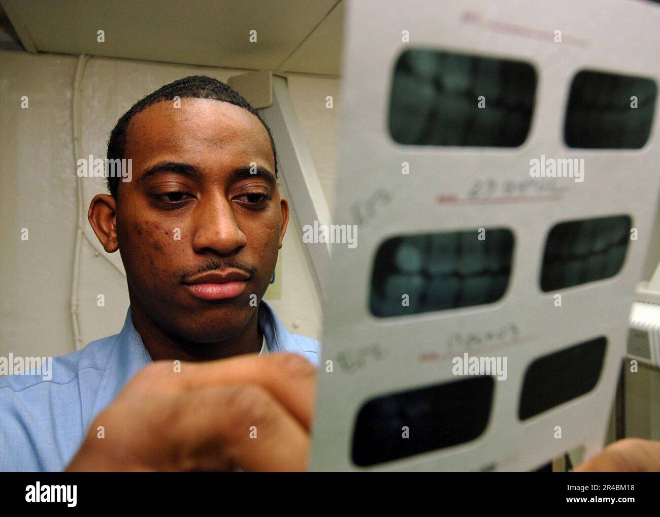 US Navy U.S. Navy Hospitalman examines X-rays of a patient's teeth in ...