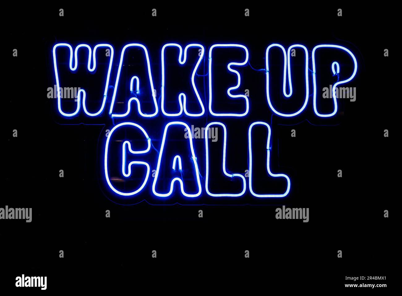 A bright neon sign of 'Wake Up Call' illuminated in the darkness ...
