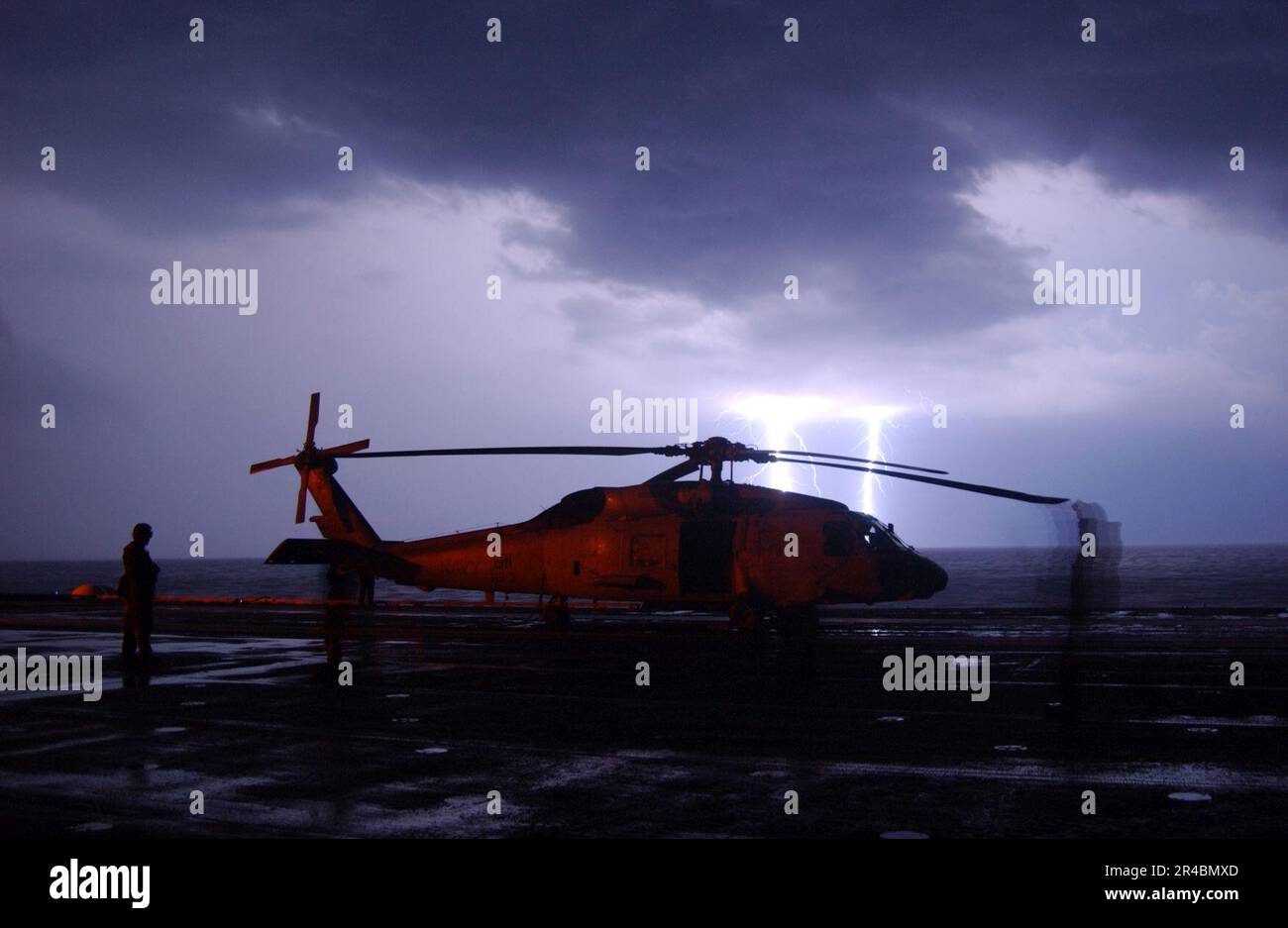US Navy Lightning strikes in the distance behind an SH-60F Seahawk ...