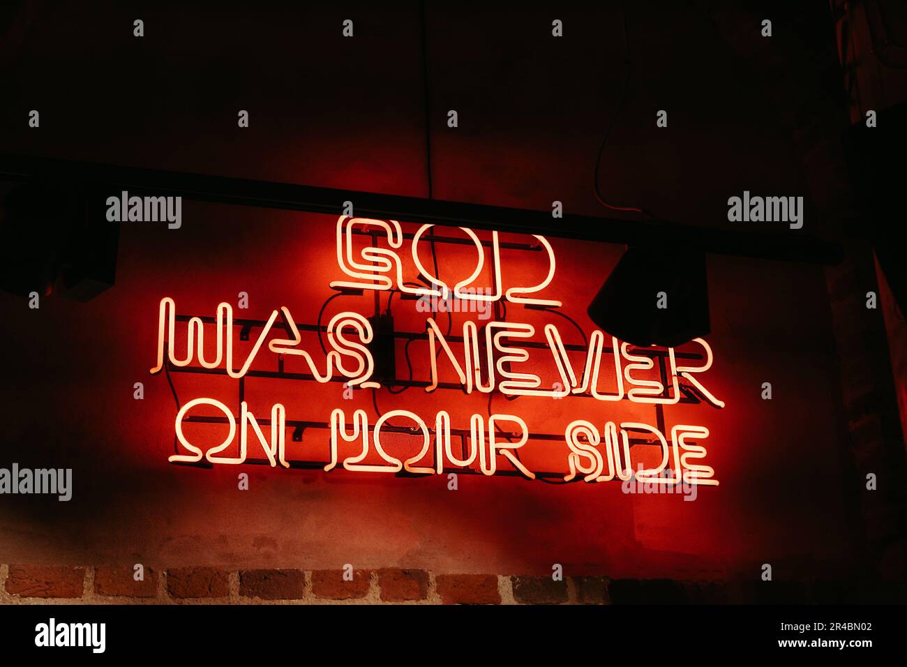 A brightly lit neon sign with the phrase "God Was Never On Our Side" in ...