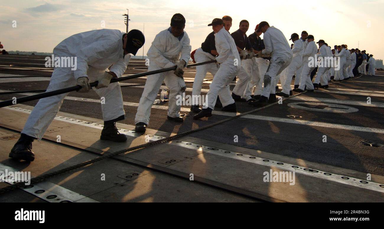 US Navy Personnel pull a line across the flight deck of the Nimitz ...