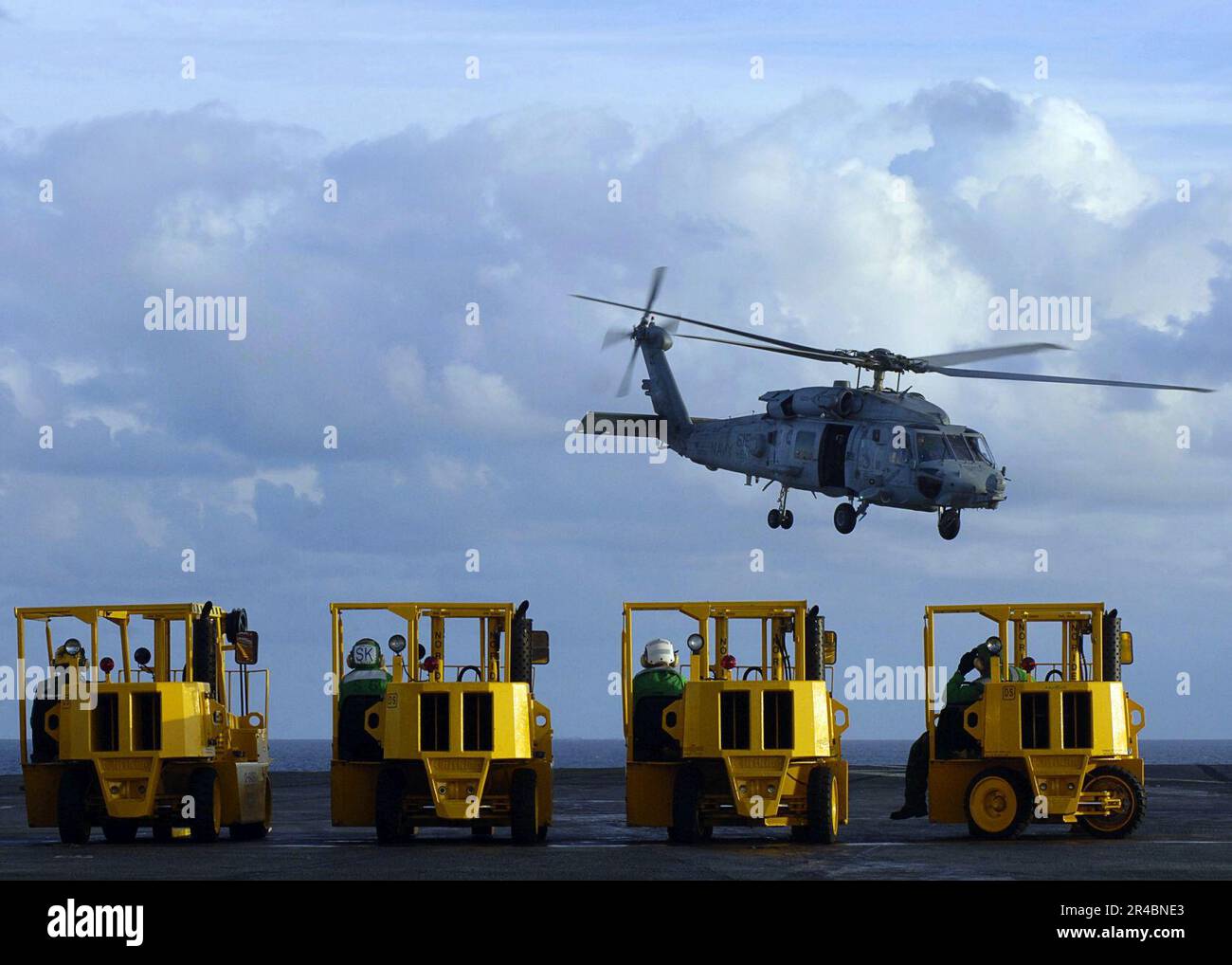 US Navy Supply Department personnel standby in forklifts to move ...