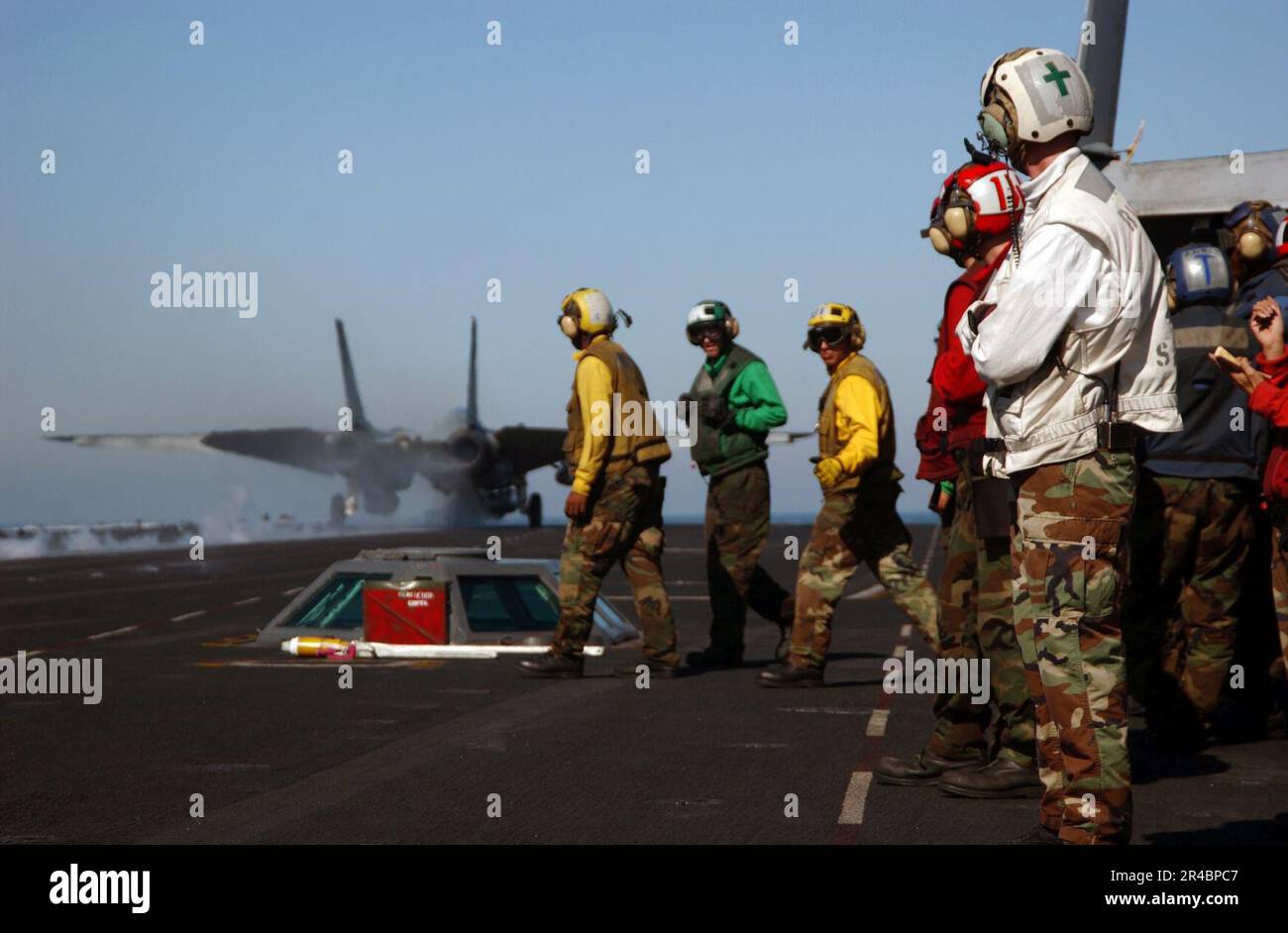 US Navy Flight deck personnel watch from the foul line as an F-14D ...