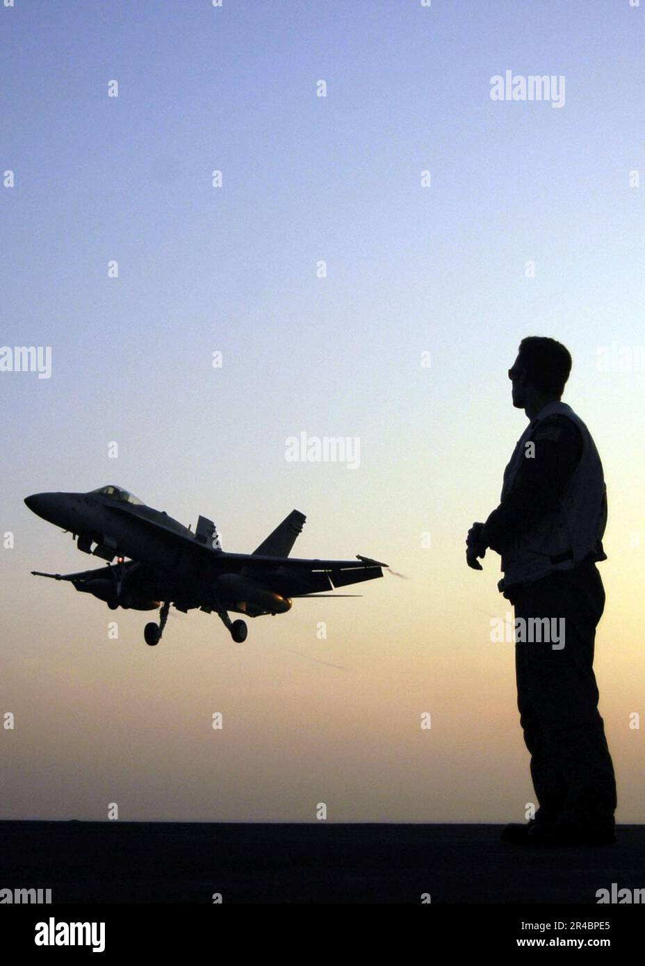US Navy A landing signal officer (LSO) observes an F-A-18C Hornet as it ...