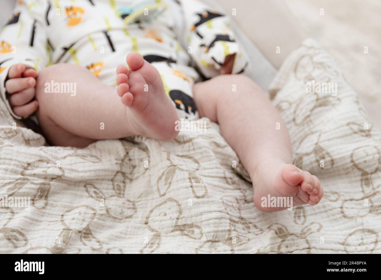 A young infant lying on its side wearing a onesie with an animal print ...