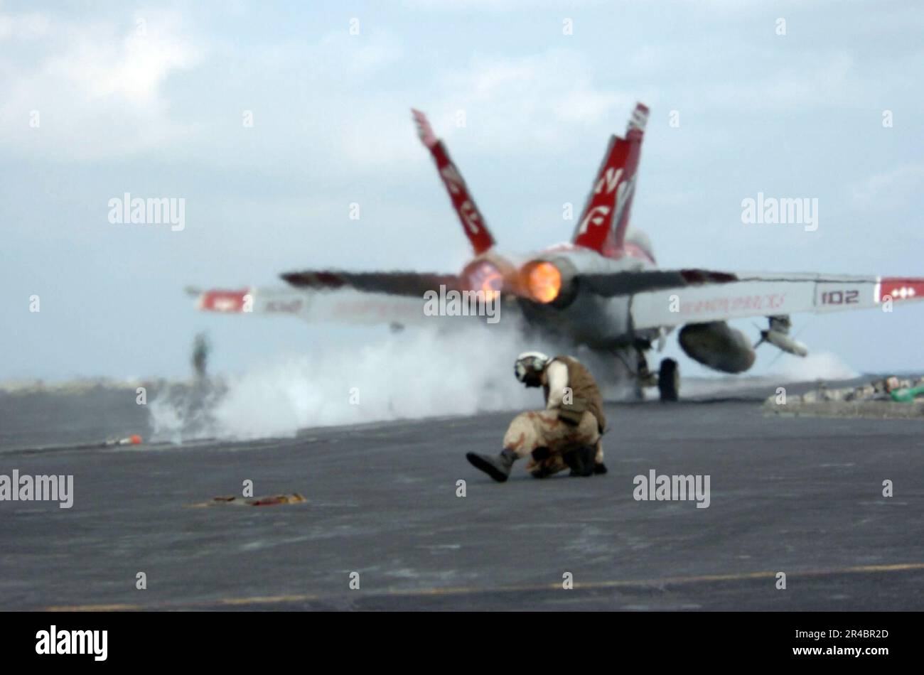 US Navy A squadron troubleshooter ducks to avoids the jet blast of one ...