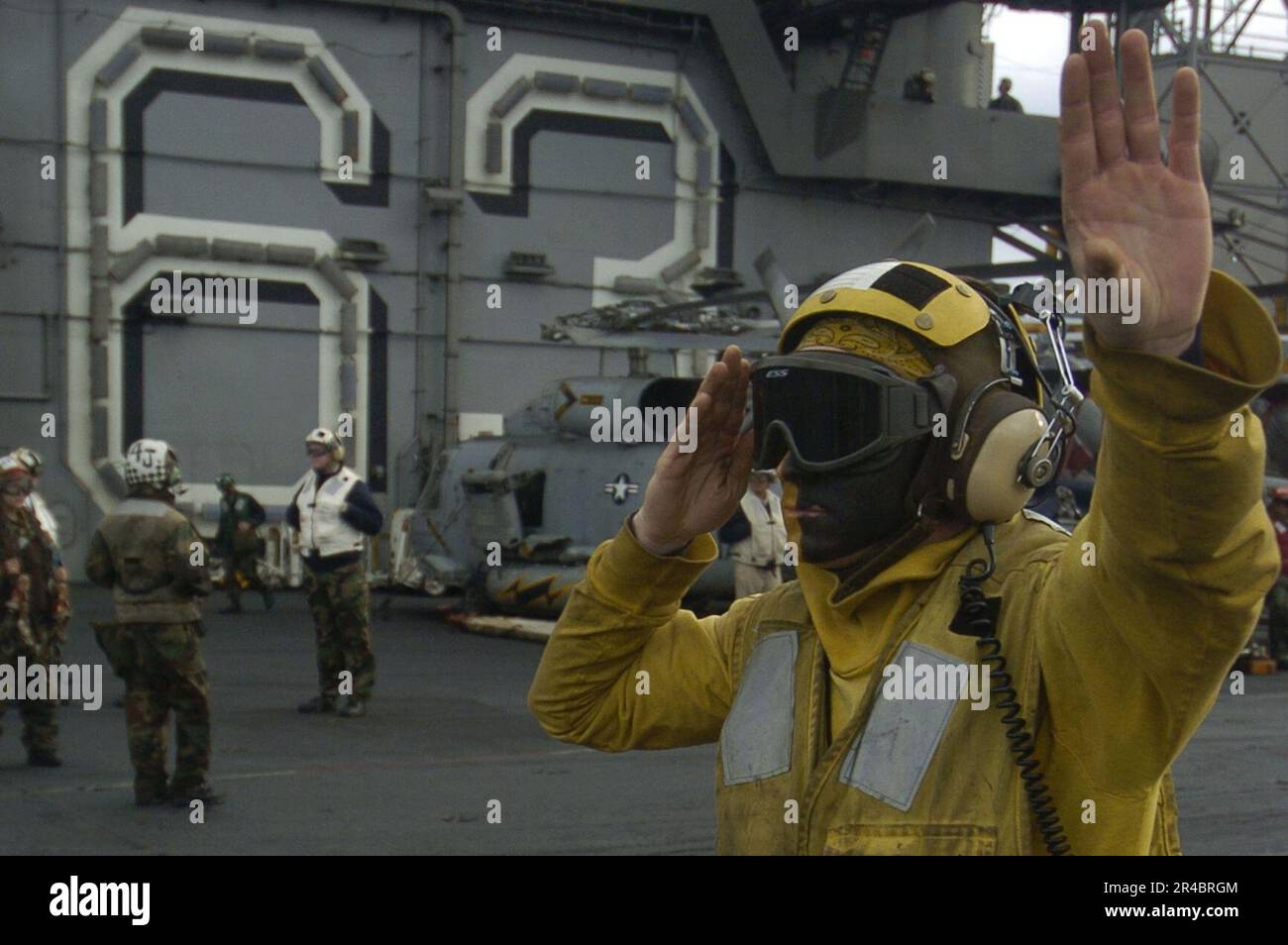 US Navy With a painted face, an aircraft director signals an F-A-18E ...