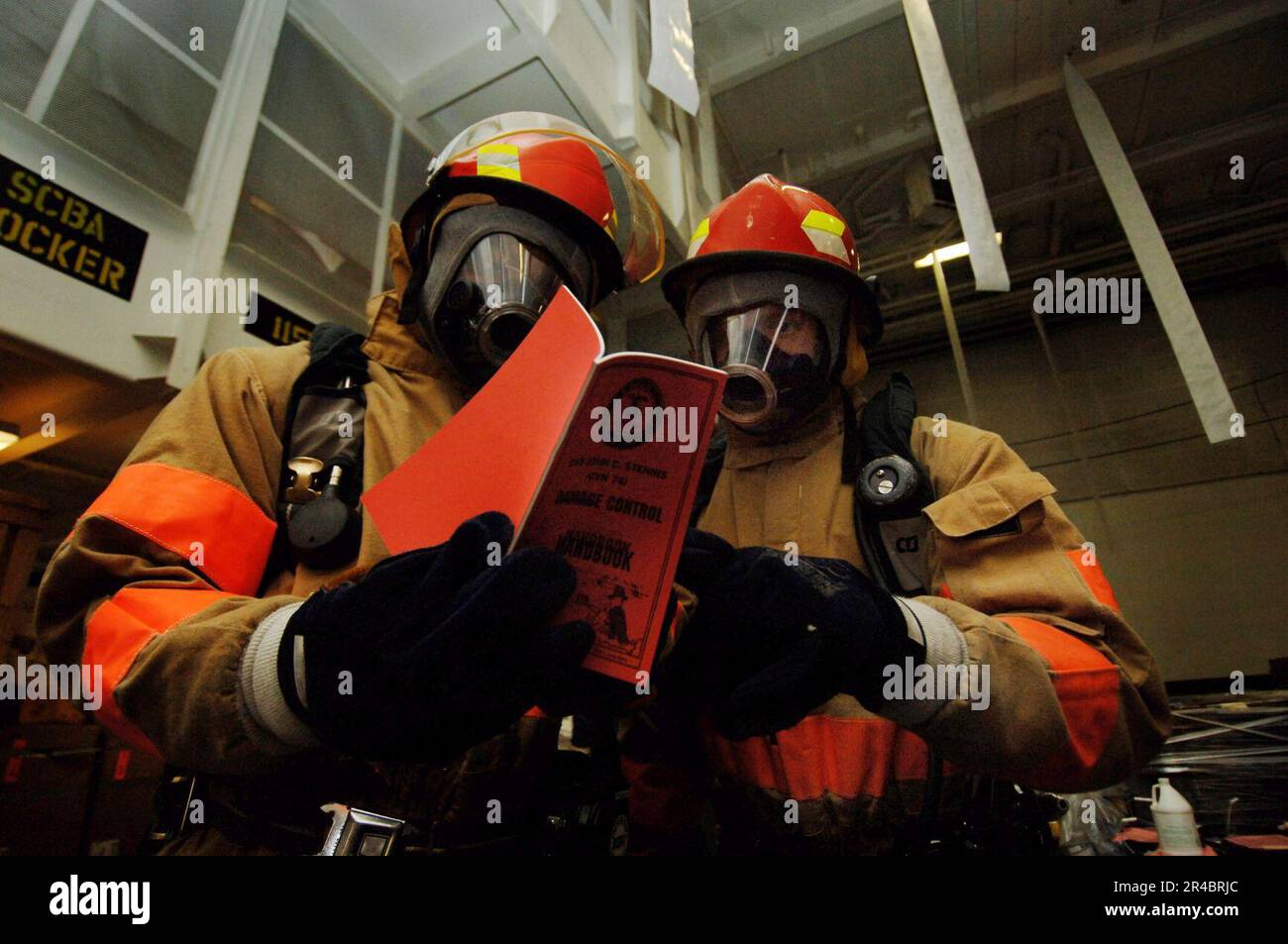 US Navy Two repair locker members review the damage control handbook ...