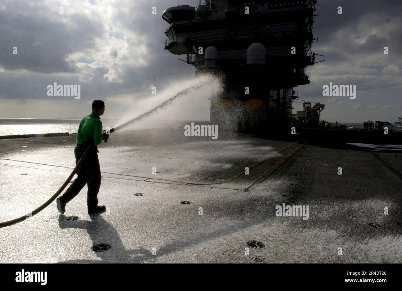 US Navy Airman uses a fire hose and sprays off the flight deck after ...